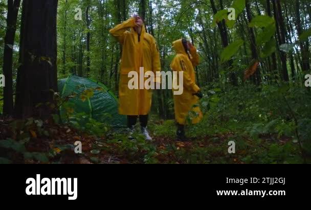 Wide shot two scared young women yelling walking at camp site in rainy ...