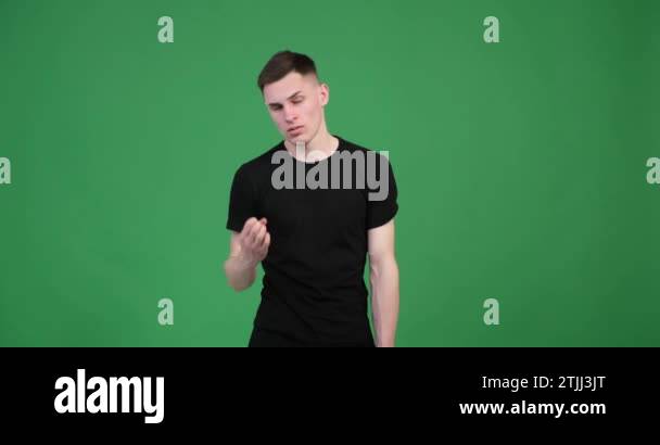 A Caucasian man on a green screen background, visibly bored and ...