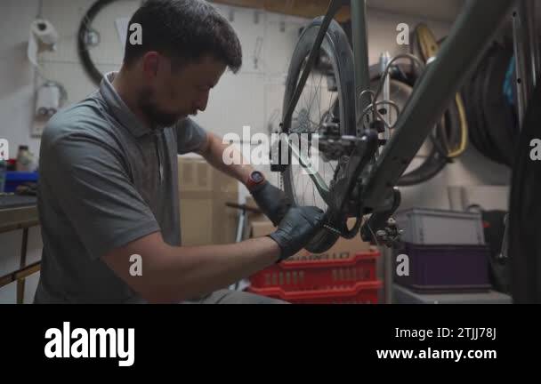 Man bicycle mechanic installs cycle chain on bike. Technician fixes ...