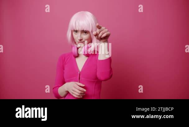 Static shot of young female with wireless headphones and bright wig ...