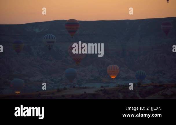 Balloons against backdrop of mountains and pink sky without clouds ea ...