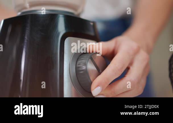 Close-up female hand turning knob on blender mixing smoothie and ...