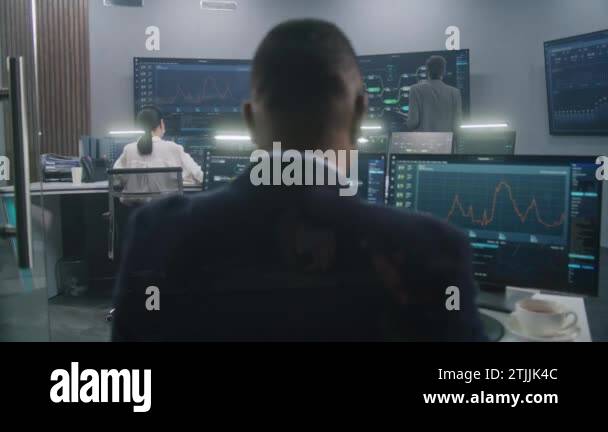 African American IT engineer works at computer with displayed real-time ...