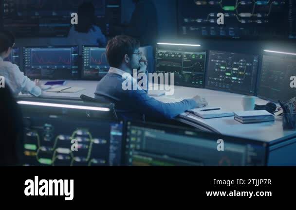 Software engineer works at computer in monitoring room late night. Big ...