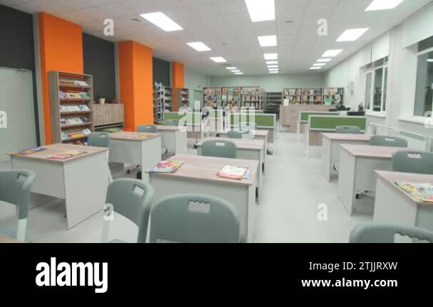 Empty reading room with small desks and bookshelves at school. Brightly ...