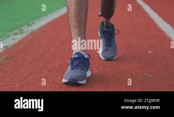 Front view of a disabled athlete man with prosthetic leg walking on ...