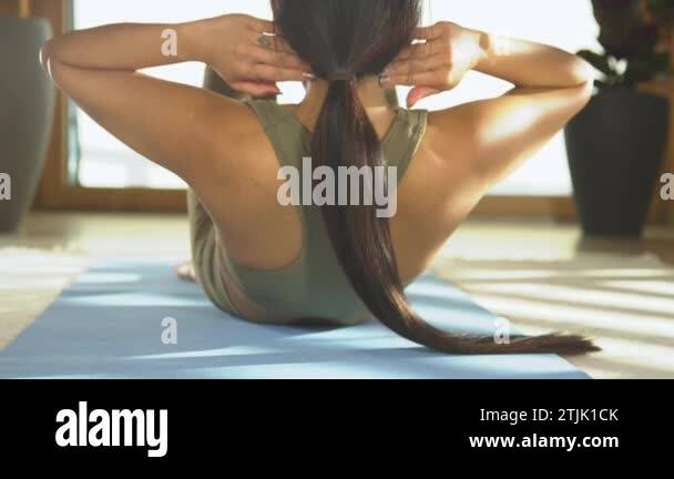 CLOSE UP: Back view of a young lady at fitness exercises for abdominal ...
