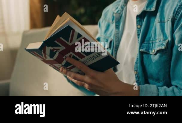 A handsome college student reads an English dictionary while sitting on ...