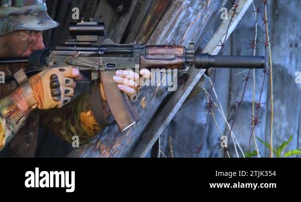 Ambush shooting. Close-up 4k video of a mercenary soldier fires an ...