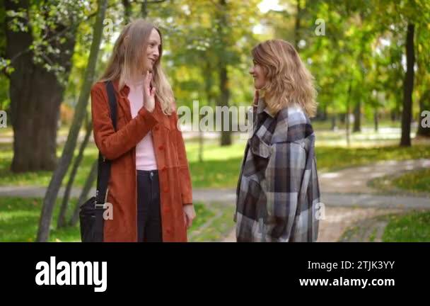 Positive Caucasian woman saying goodbye to friend walking away on sunny ...