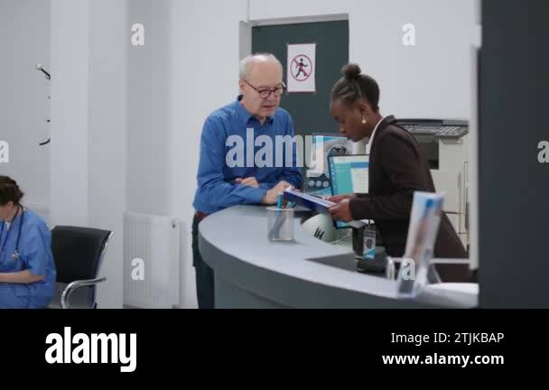 Receptionist and senior patient talking about medical report and ...