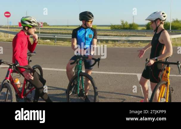 Two caucasian men and one woman smiling and talking while resting after ...
