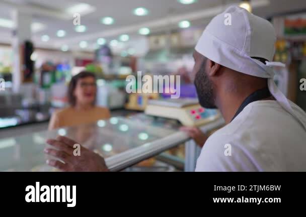 Back of an employee behind cafeteria counter speaking with customer. A ...