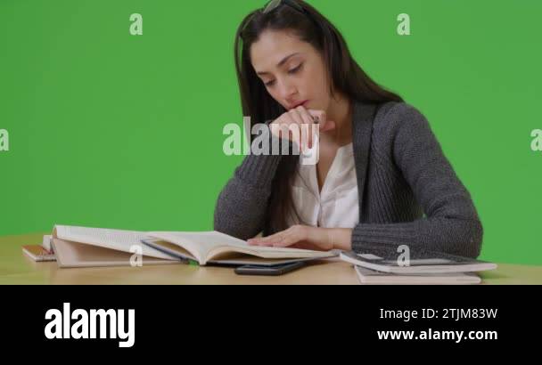 A college student does her homework at her desk in her room on green ...