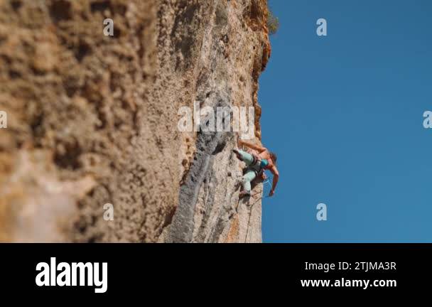 bottom view of muscular strong man rock climber climbs on vertical ...