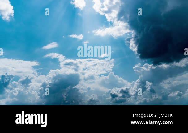 White fluffy clouds slowly float through the blue daytime sky timelapse ...
