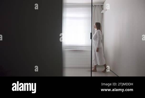 Woman in robes open Transparent sliding door inside the modern bathroom ...