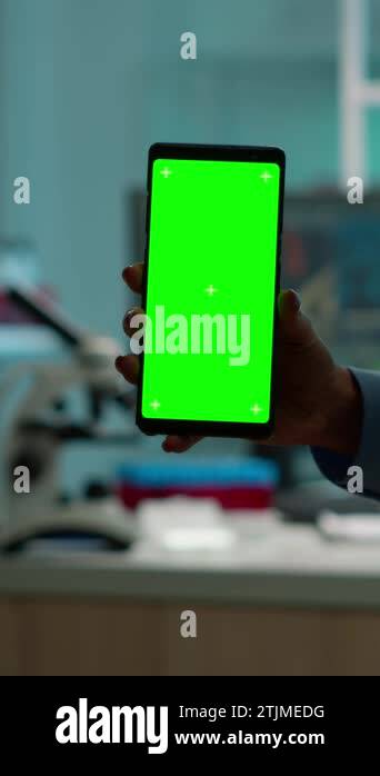 Vertical video: Close up of chemists hand holding smartphone with green ...