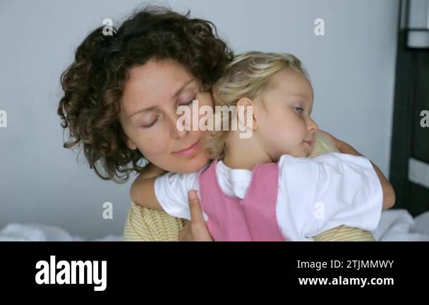 Caring woman embraces her sad melancholic baby girl, calming her and ...