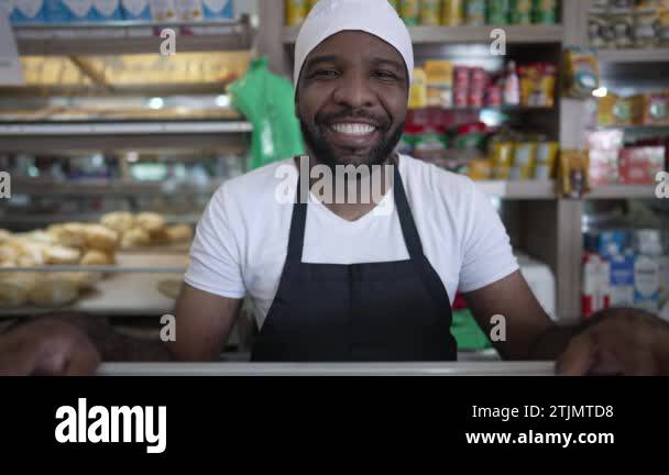 One happy black employee of grocery store smiling behind counter with ...