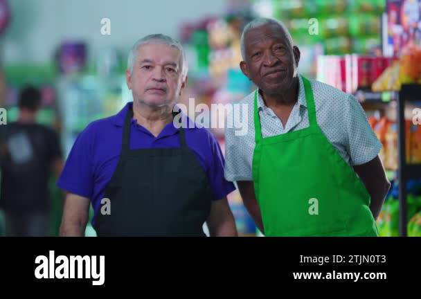 Two senior diverse employees of supermarket business looking at camera ...
