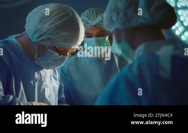 A male doctor wearing a full surgeons uniform is performing intense ...