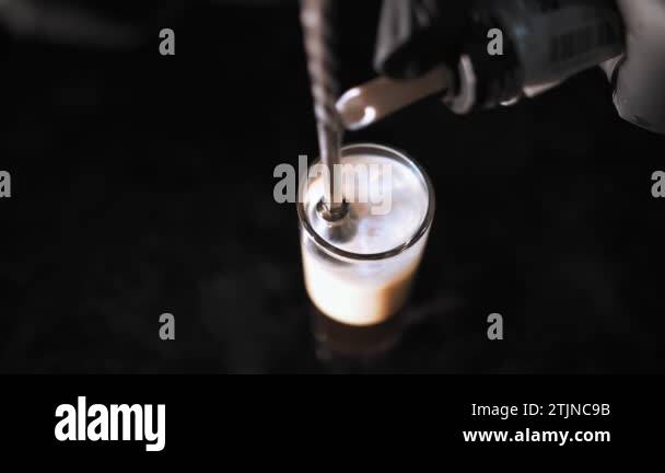 Cocktail Shots. close-up. bartender is pouring different alcoholic drinks in layers, into shot ...