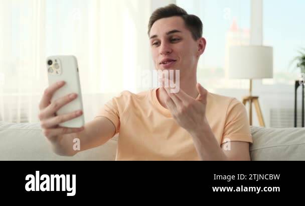 A friendly man sitting comfortably on the sofa, engaging in a video ...