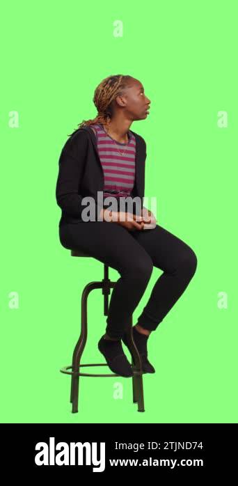 Vertical video: African american person sitting on chair over full body ...