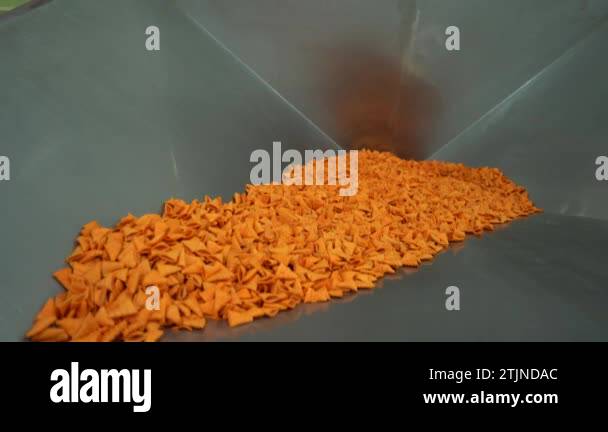 Pouring cone-shaped chips onto the production line in a food factory ...