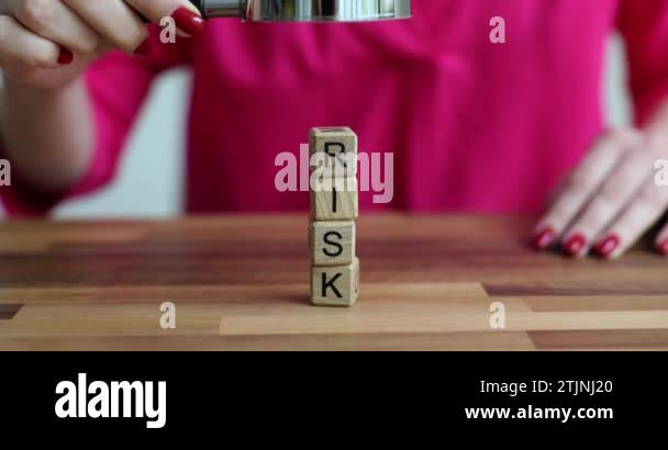 Woman is looking at wooden blocks with word risk using magnifying glass ...