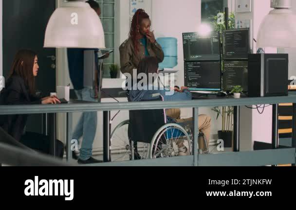 Asian programer with chronic impairment working on software code with it engineer in agency ...