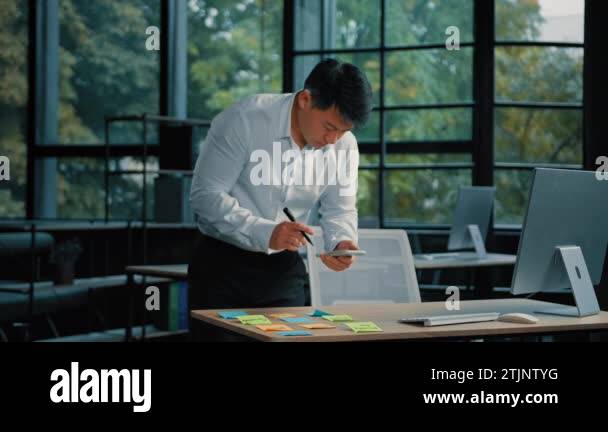 Korean asian employee businessman stand at desk in office write on memo ...