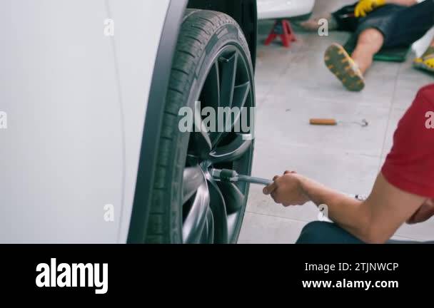 Auto mechanic man changing a wheel on a luxury white car using balloon ...