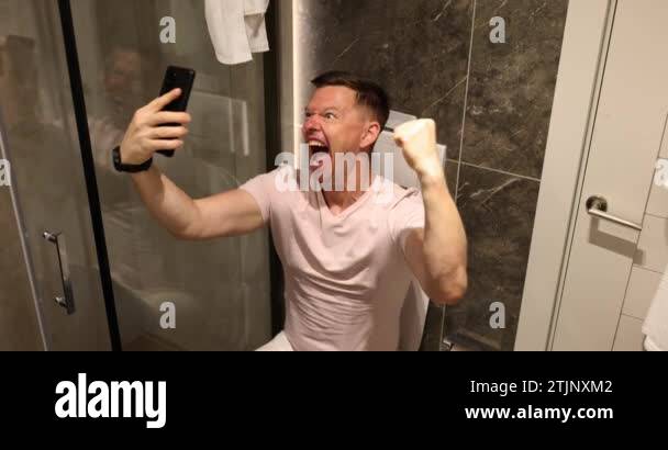 Surprised happy holding phone looking at mobile smartphone sitting on ...