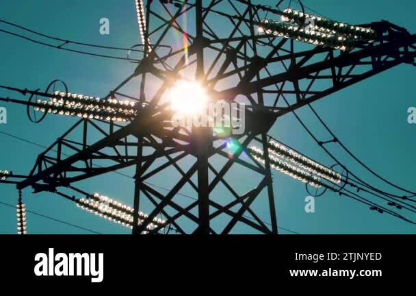 Power lines with sun rays on blue sky. High voltage substation ...