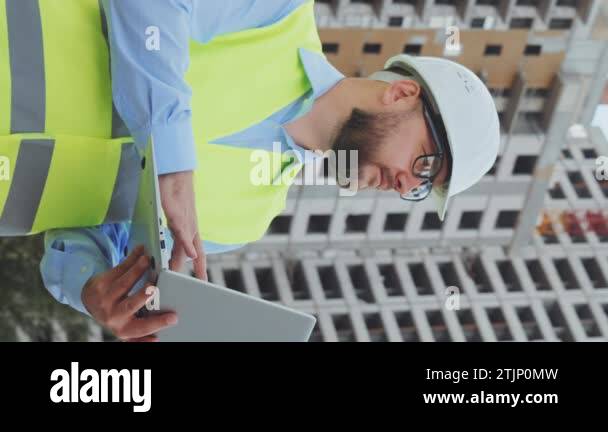 Vertical Screen: Bearded building inspector wearing hard hat and safety ...