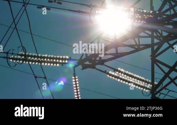Power lines with sun rays on blue sky. High voltage substation ...
