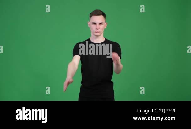 Against a vibrant green screen backdrop, a confident Caucasian man is ...
