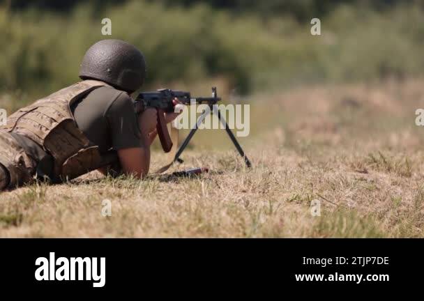 Military man in green uniform vest unloading gun with machine gun in ...