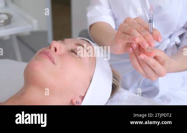 Botox therapy process. A beautician holds a needle before injecting ...