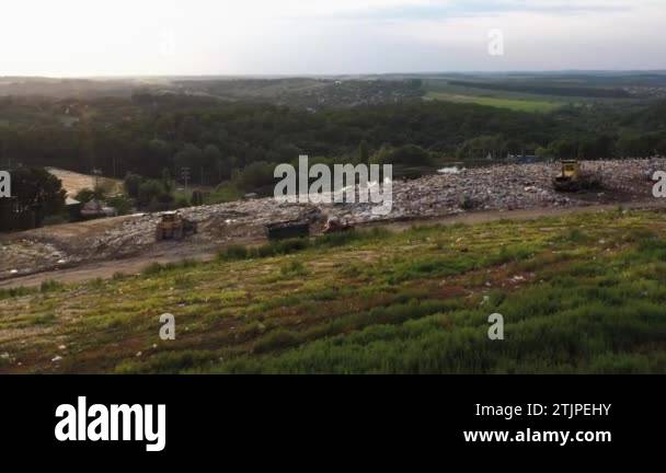 Tractor on the landfill site garbage dump in a countryside rural field ...