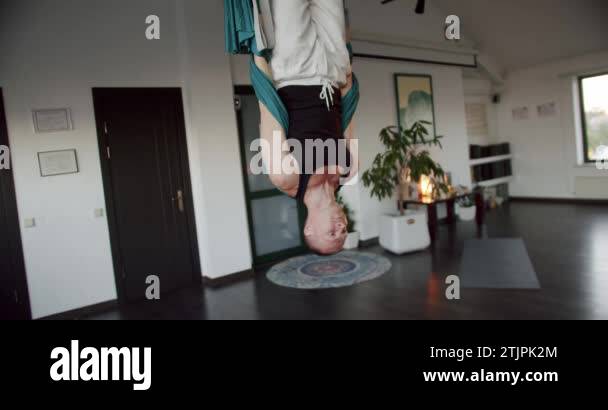 Man hanging upside down on aerial sinks. Pan around tilt down handheld ...