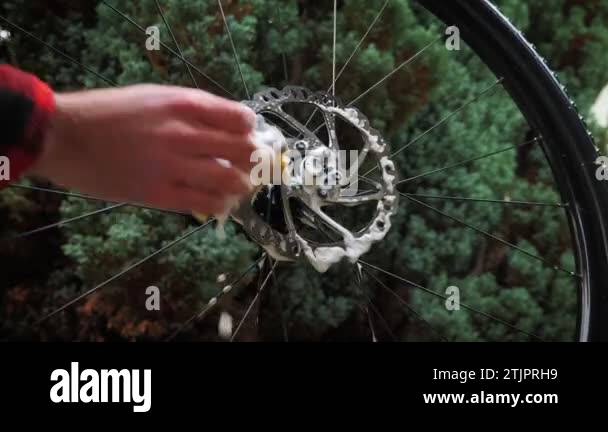 Bike mechanic cleaning bicycle wheel with soap and sponge. Man washing ...