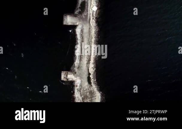 Top down view of the splashing waves over the stone breakwater pier to ...