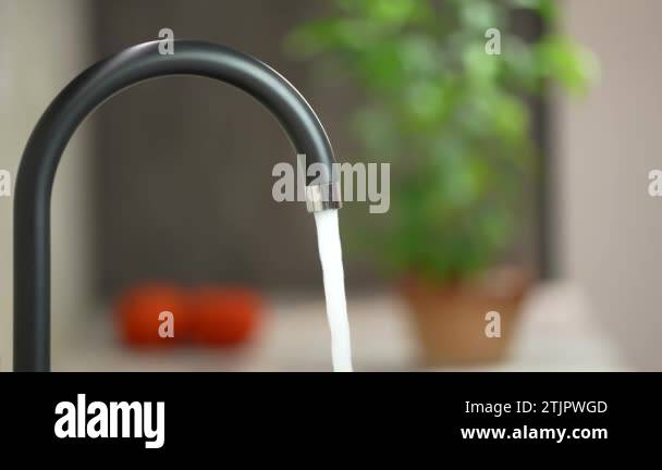 Water running from faucet in kitchen. A jet of water runs from a water ...