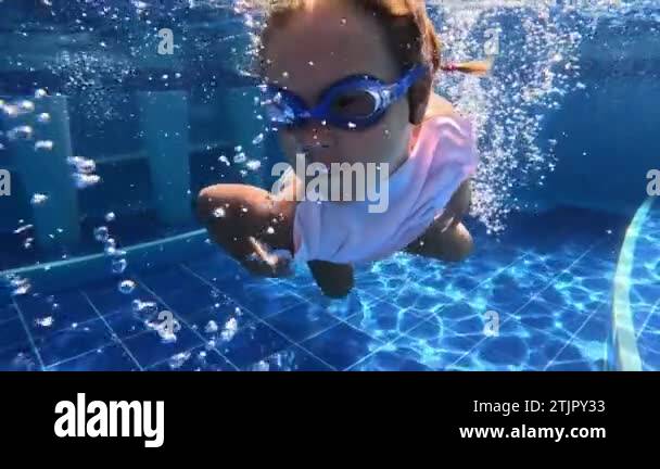 Little girl 3-5 years old learning to swim underwater in the pool with ...