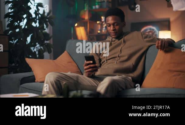 Positive African Social Connector African man on a cozy couch, chatting ...