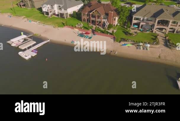 An aerial view going up and back revealing houses around a lake. The ...