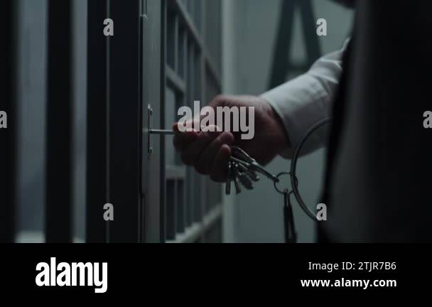 Close up of jailer opening and locking prison cell with keys. Prisoner ...